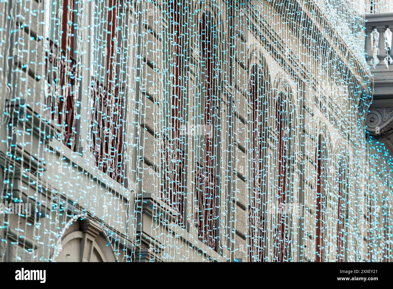 Blue christmas lights cascade down a building's exterior, creating a ...