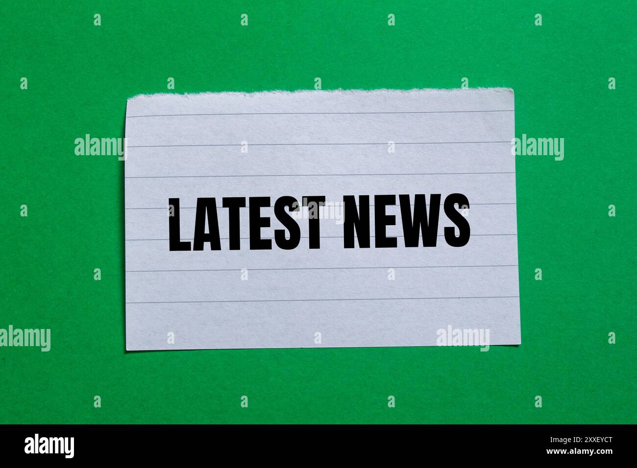 Latest news message written on ripped torn paper piece with green ...
