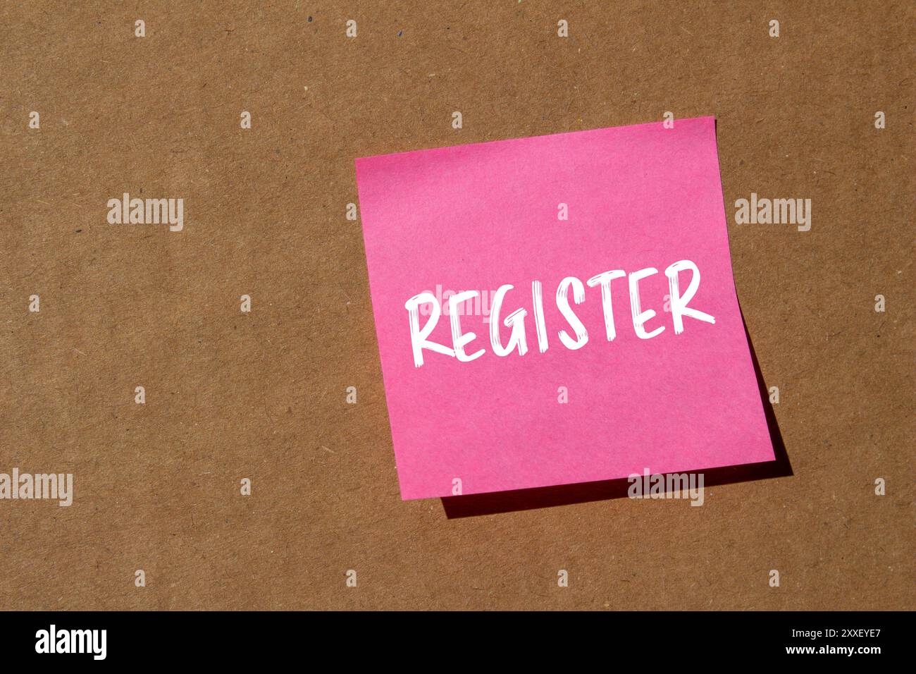 Register message written on pink paper with cardboard background ...