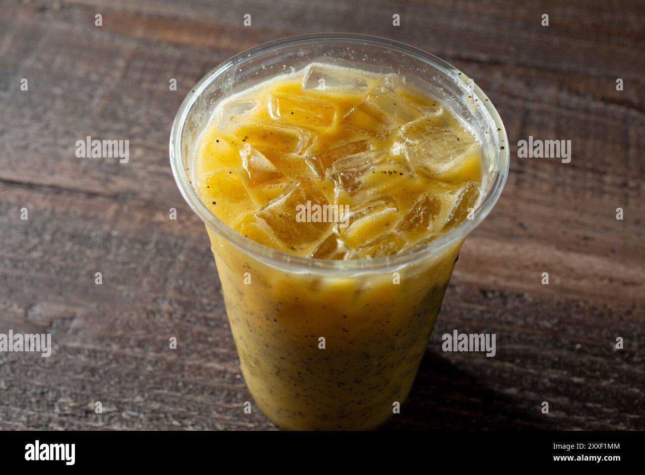 A view of a cold yellow juice drink in a plastic cup Stock Photo - Alamy