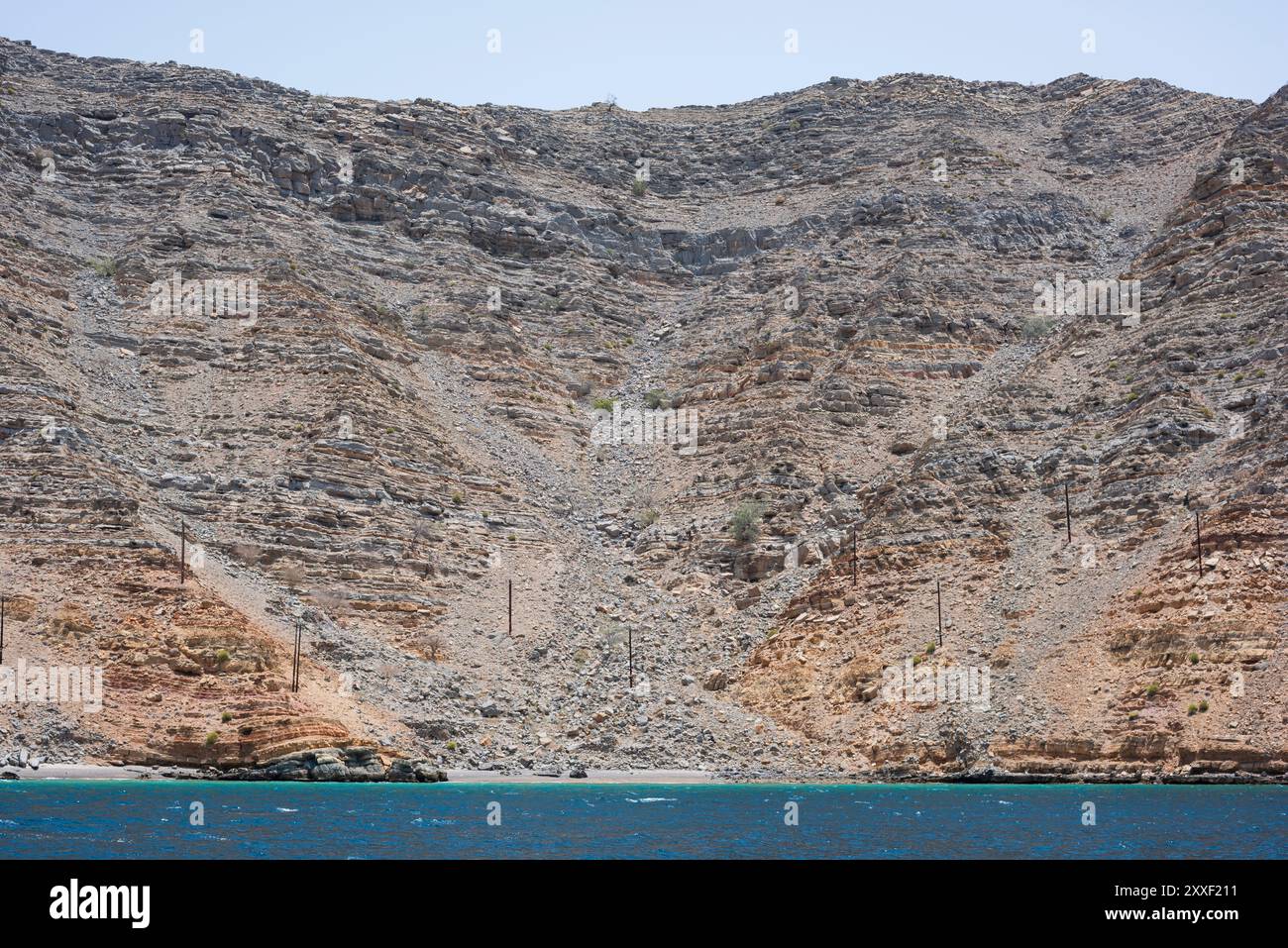 Rocky cliff and small beach in a fjord-like setting of Musandam ...