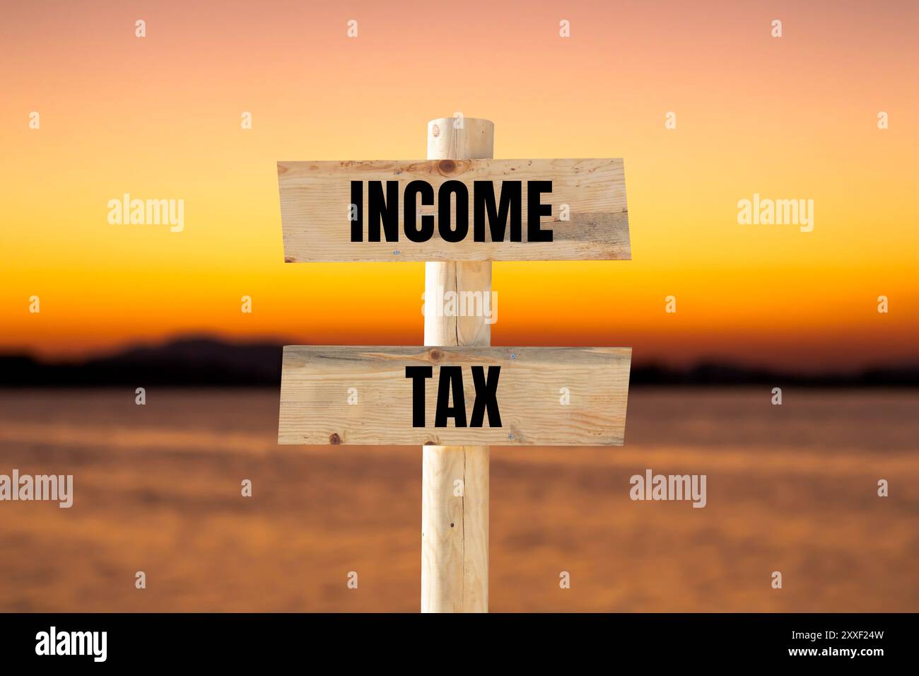 Income tax message written on wooden sign with blurry lake background ...