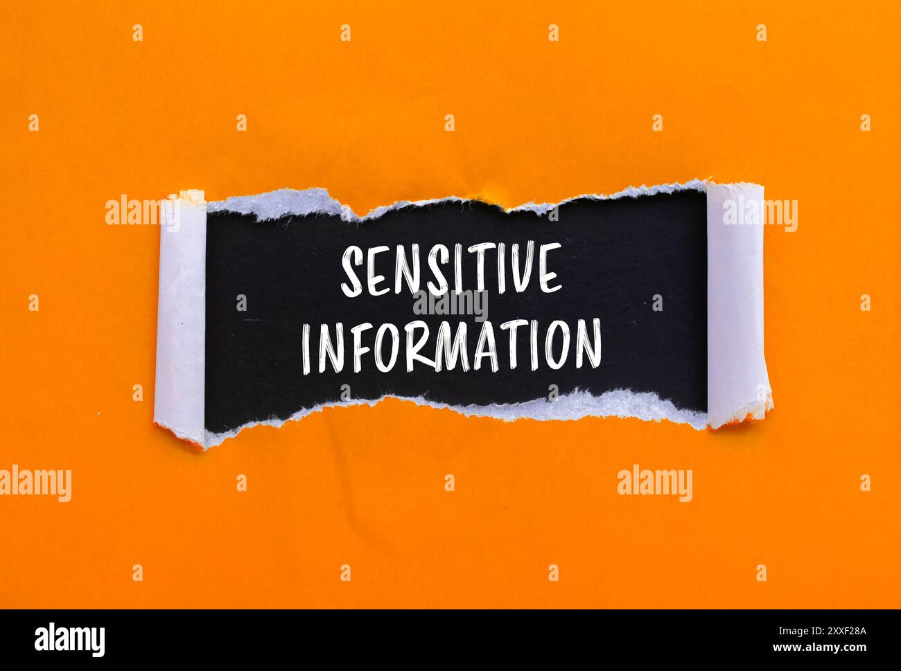 Sensitive information message written on ripped torn orange paper with ...