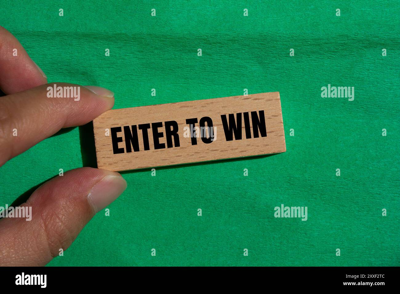 Enter to win message written on wooden block with green background ...