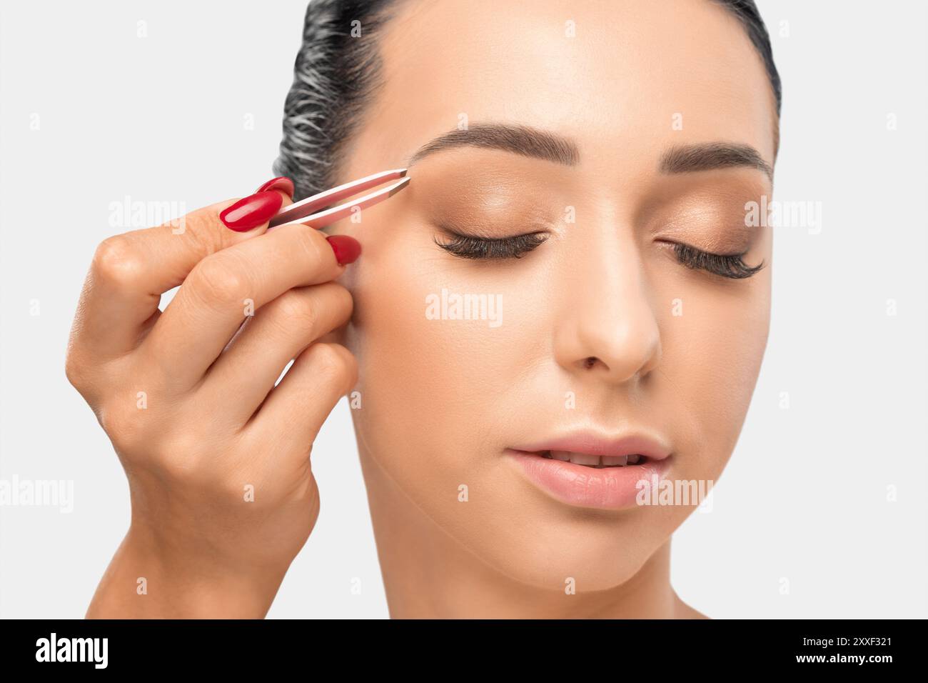 Makeup artist combs and plucks eyebrows after dyeing in a beauty salon ...