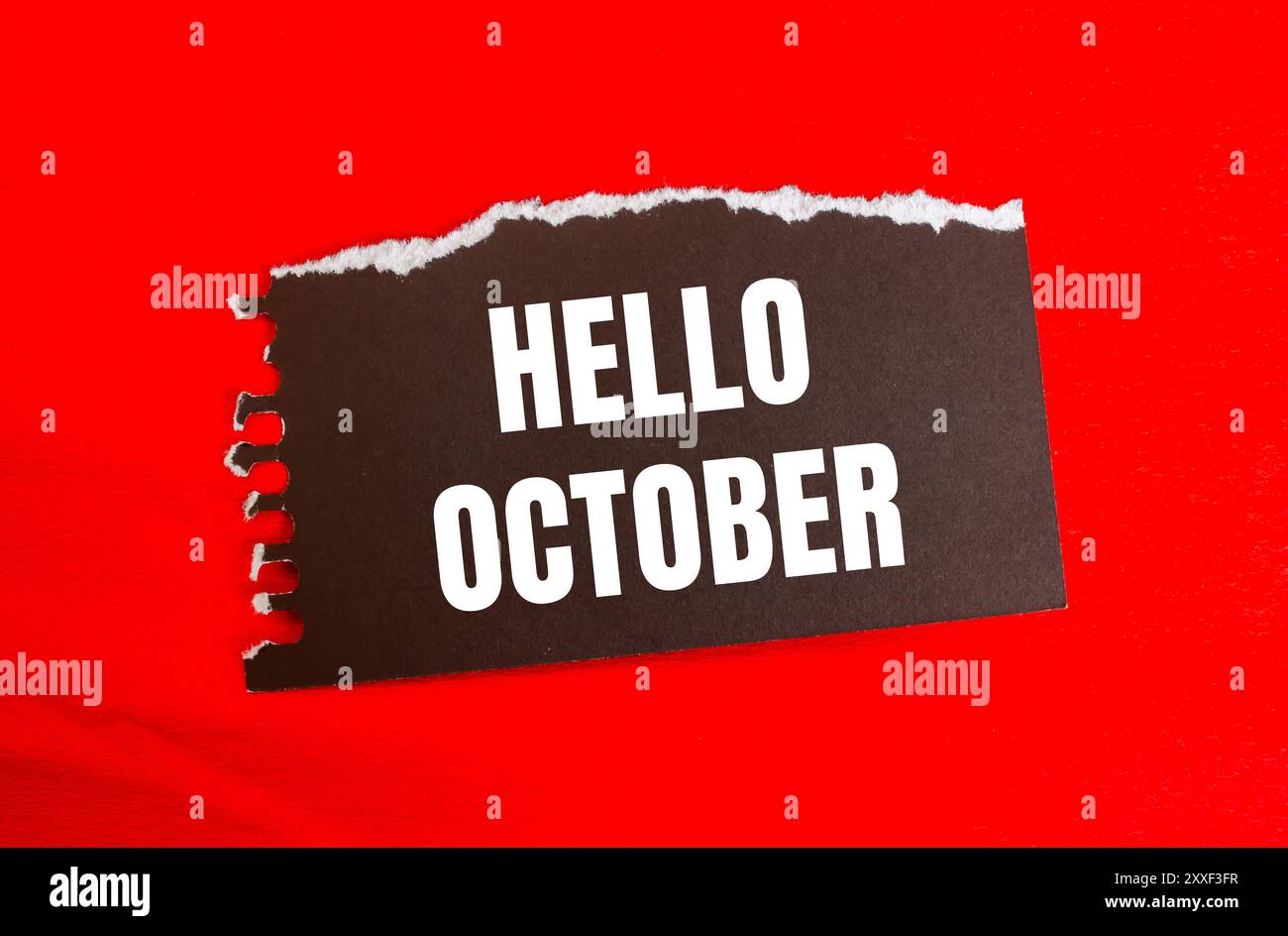 Hello october message written on ripped torn black paper piece with red ...