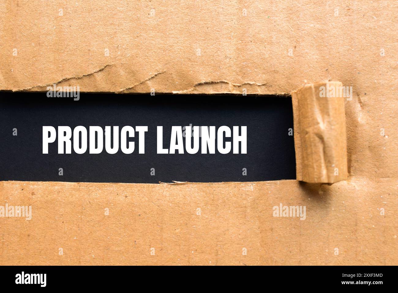 Product launch message written on ripped torn cardboard paper with black background. Conceptual ...