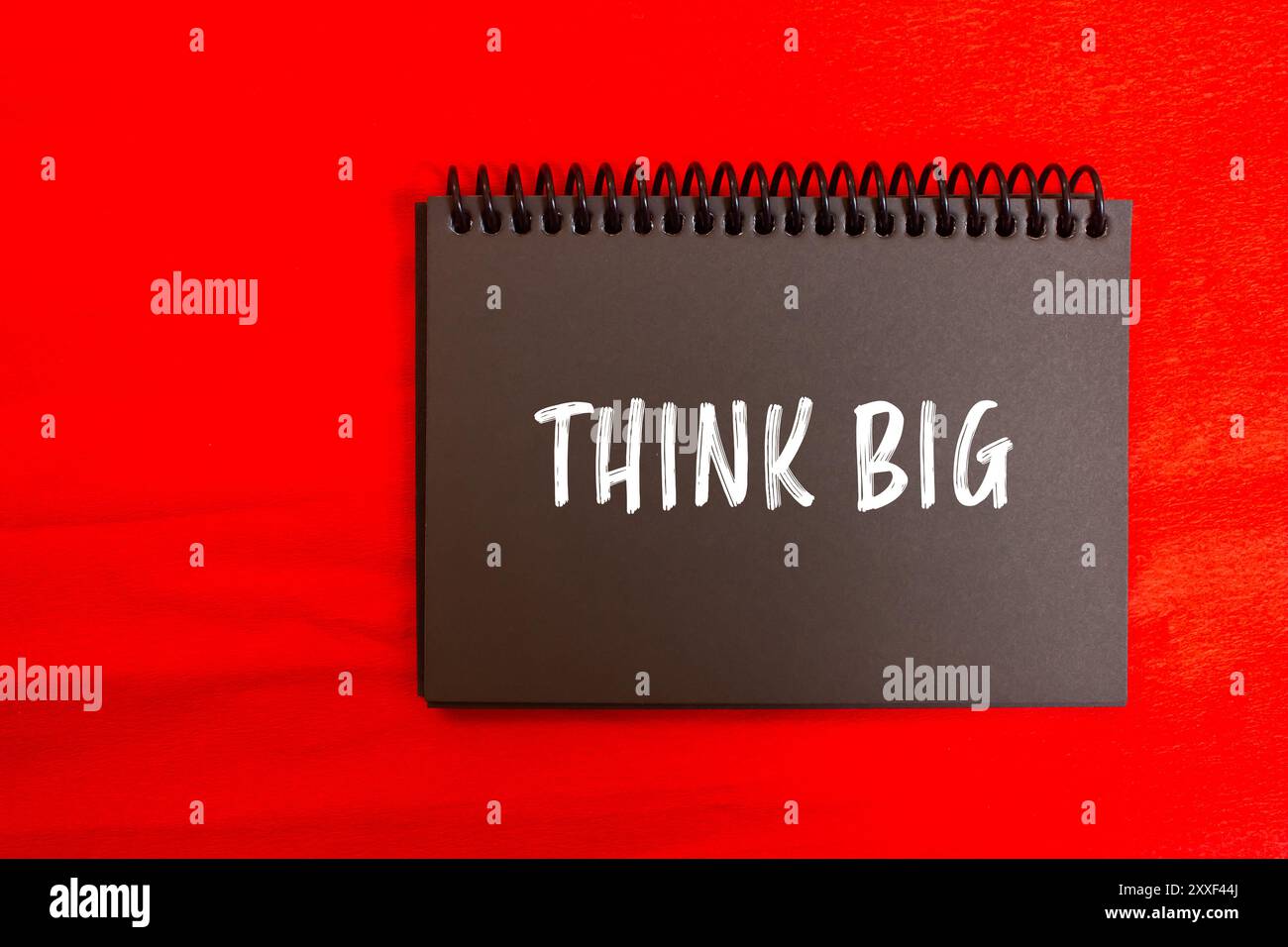 Think big message written on black notebook page with red background ...