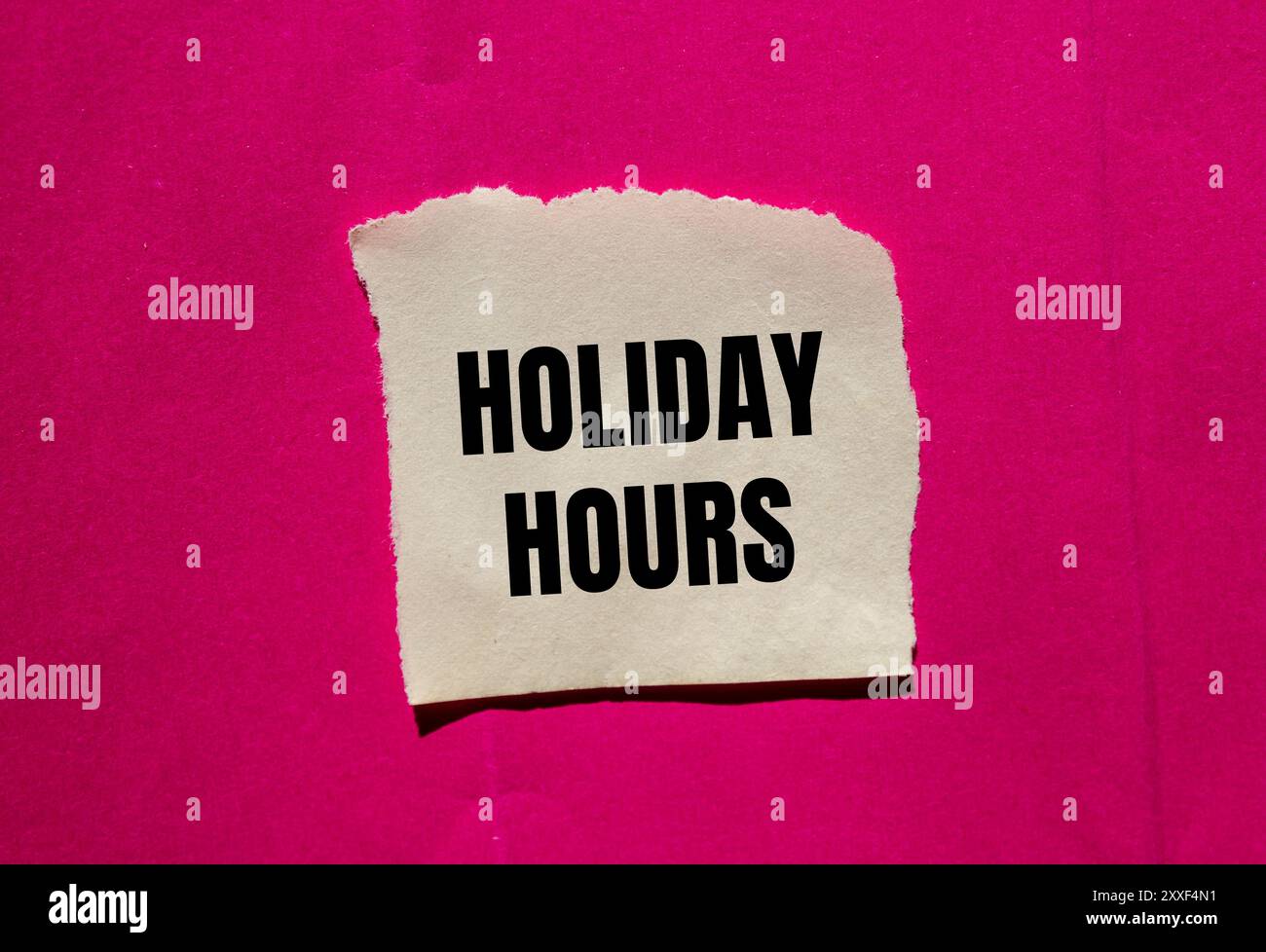 Holiday hours message written on ripped torn paper piece on pink ...