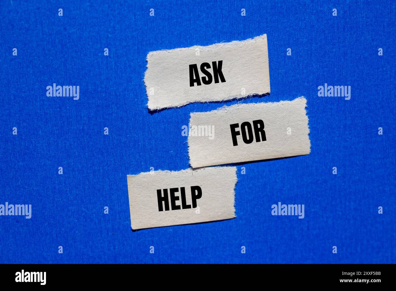 Ask for help message written on ripped torn paper peices with blue ...
