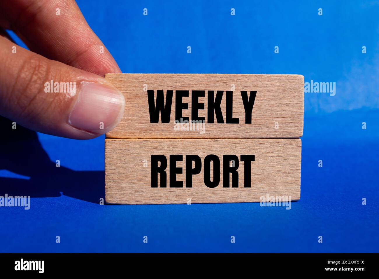 Weekly report message written on wooden blocks with blue background ...