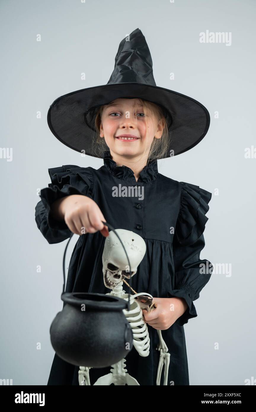 Portrait of a little Caucasian girl in a witch costume holding a ...