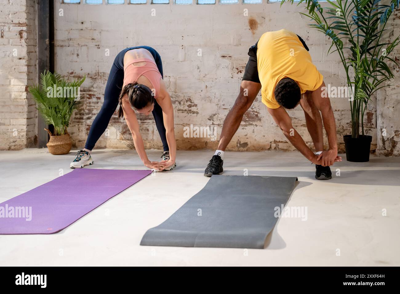 Mixed race sporty man and girl doing exercise together in a industrial ...