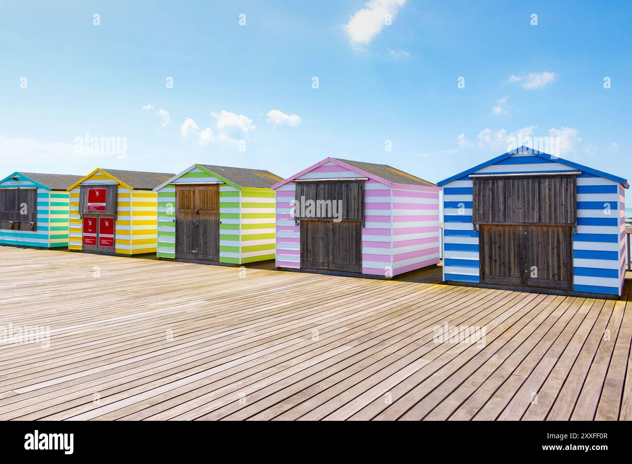 Colorful striped beach huts lined up on a wooden promenade under a ...