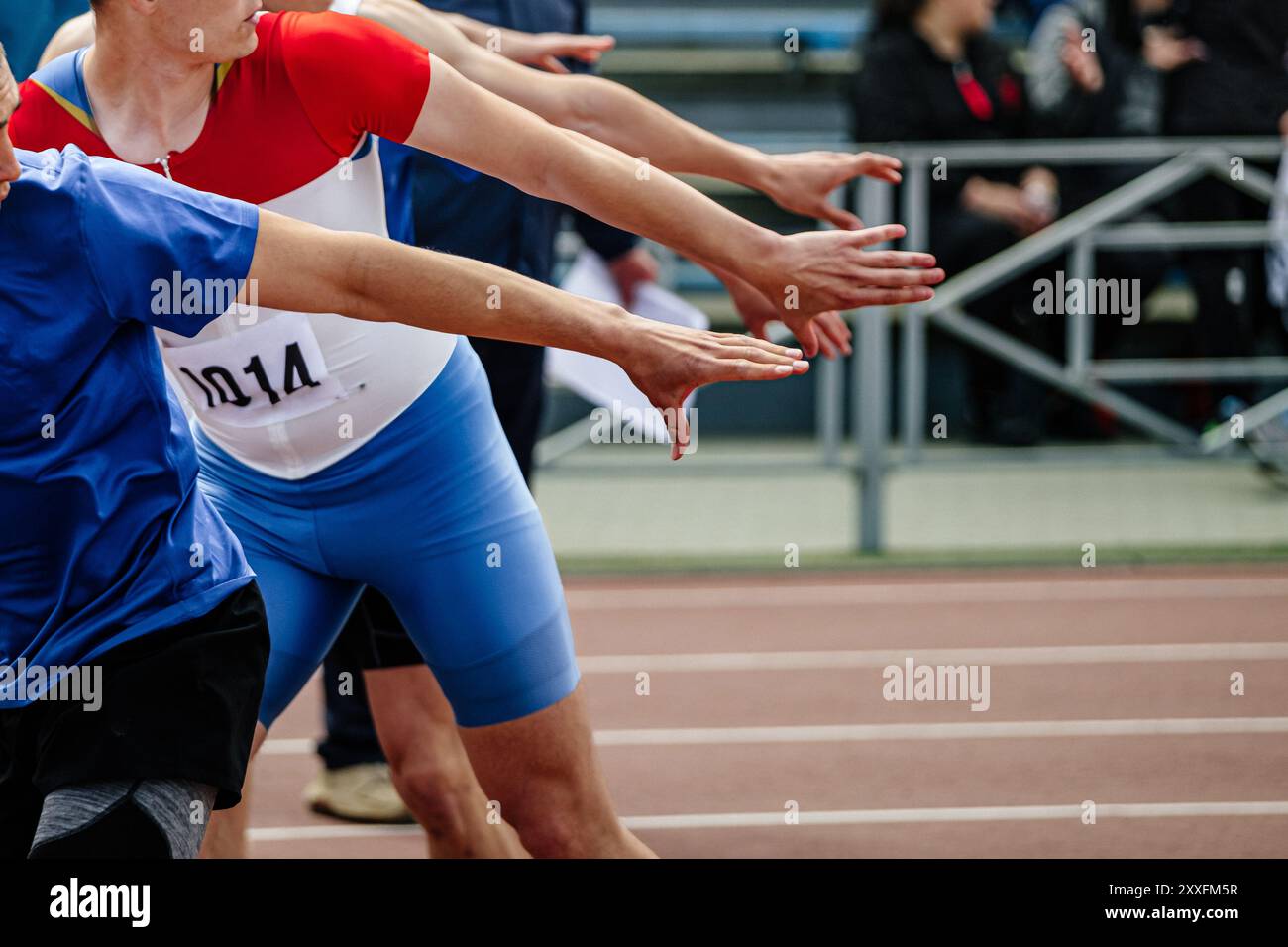 four hands of athletes waiting to pass baton in athletics competition ...