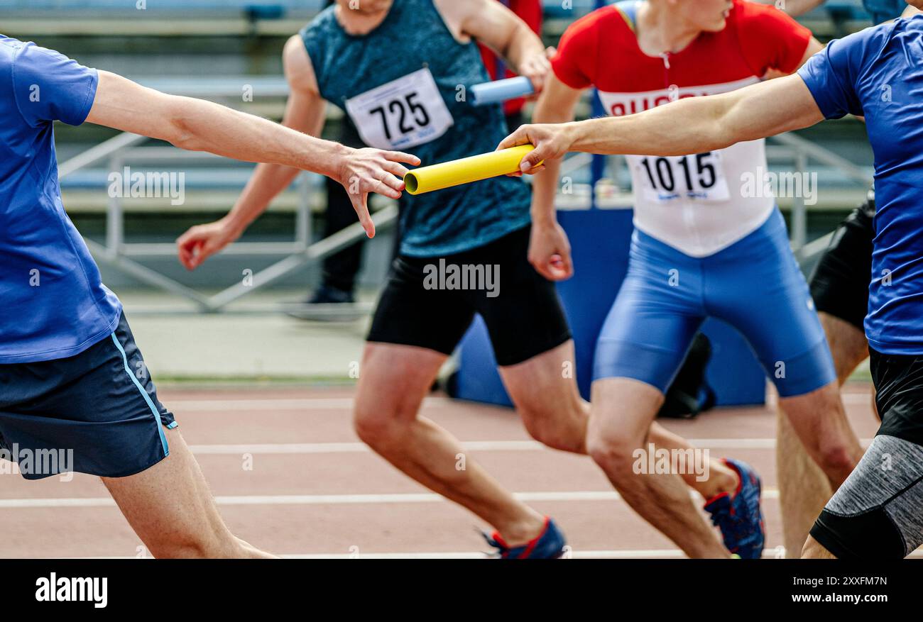 passing baton to men team athletes in athletics relay race Stock Photo ...