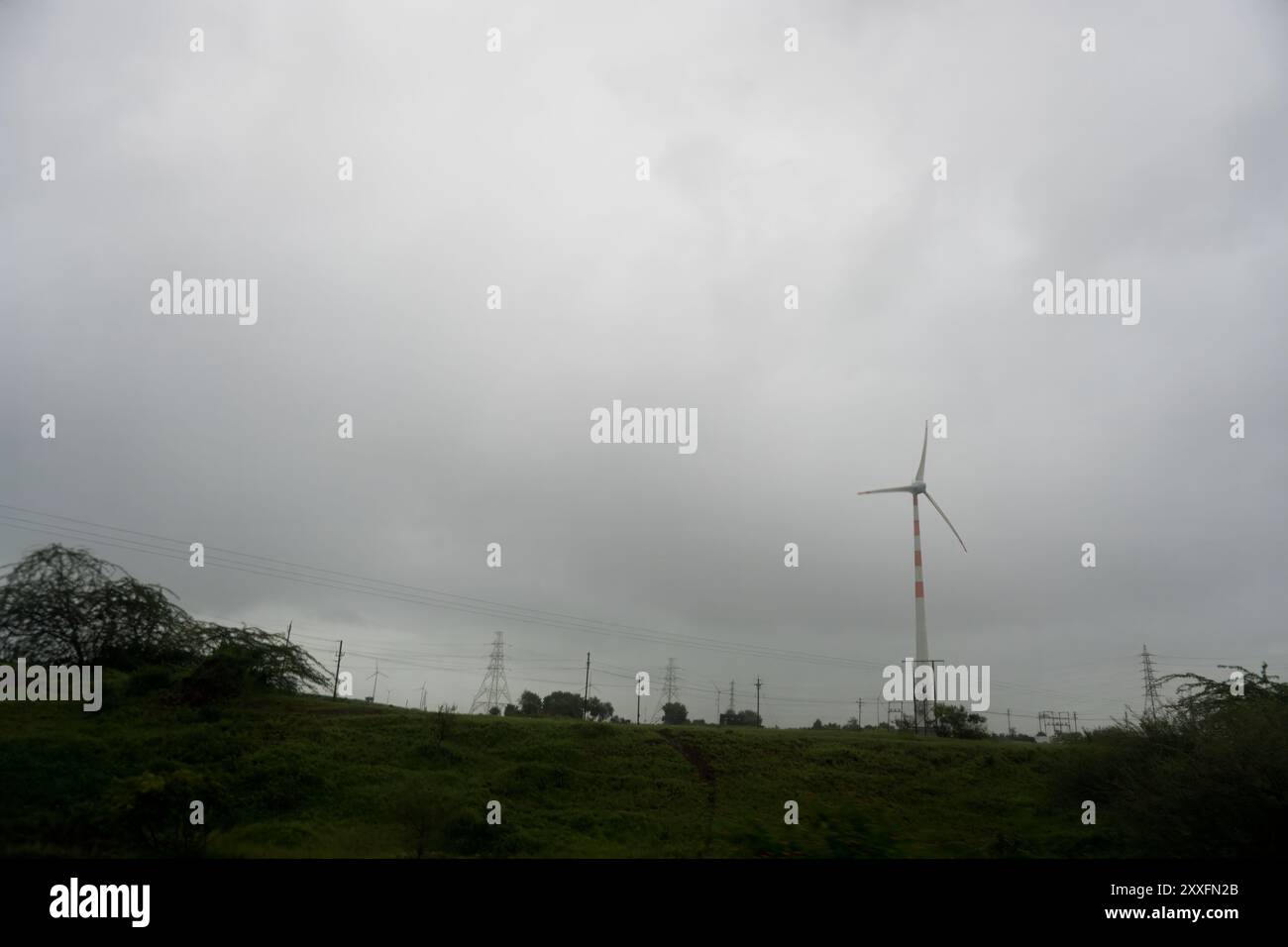 A cloudy sky frames wind turbines and power lines, emphasizing the role ...