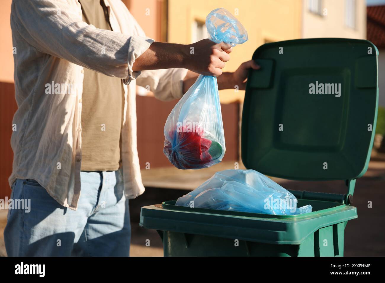 Man throwing trash bag into bin outdoors, closeup Stock Photo - Alamy