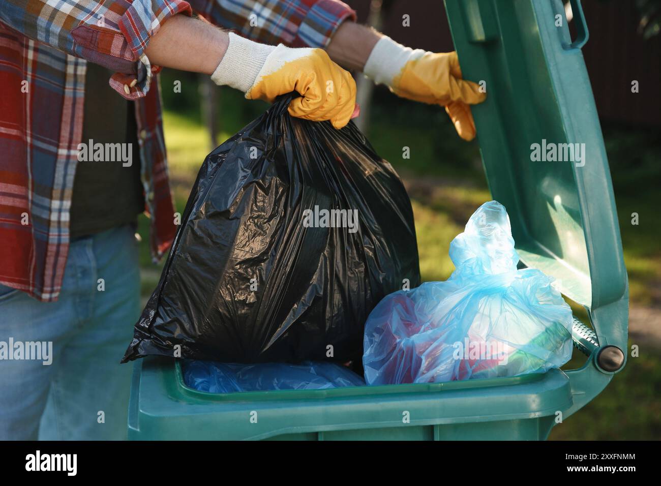Man throwing trash bag into bin outdoors, closeup Stock Photo - Alamy