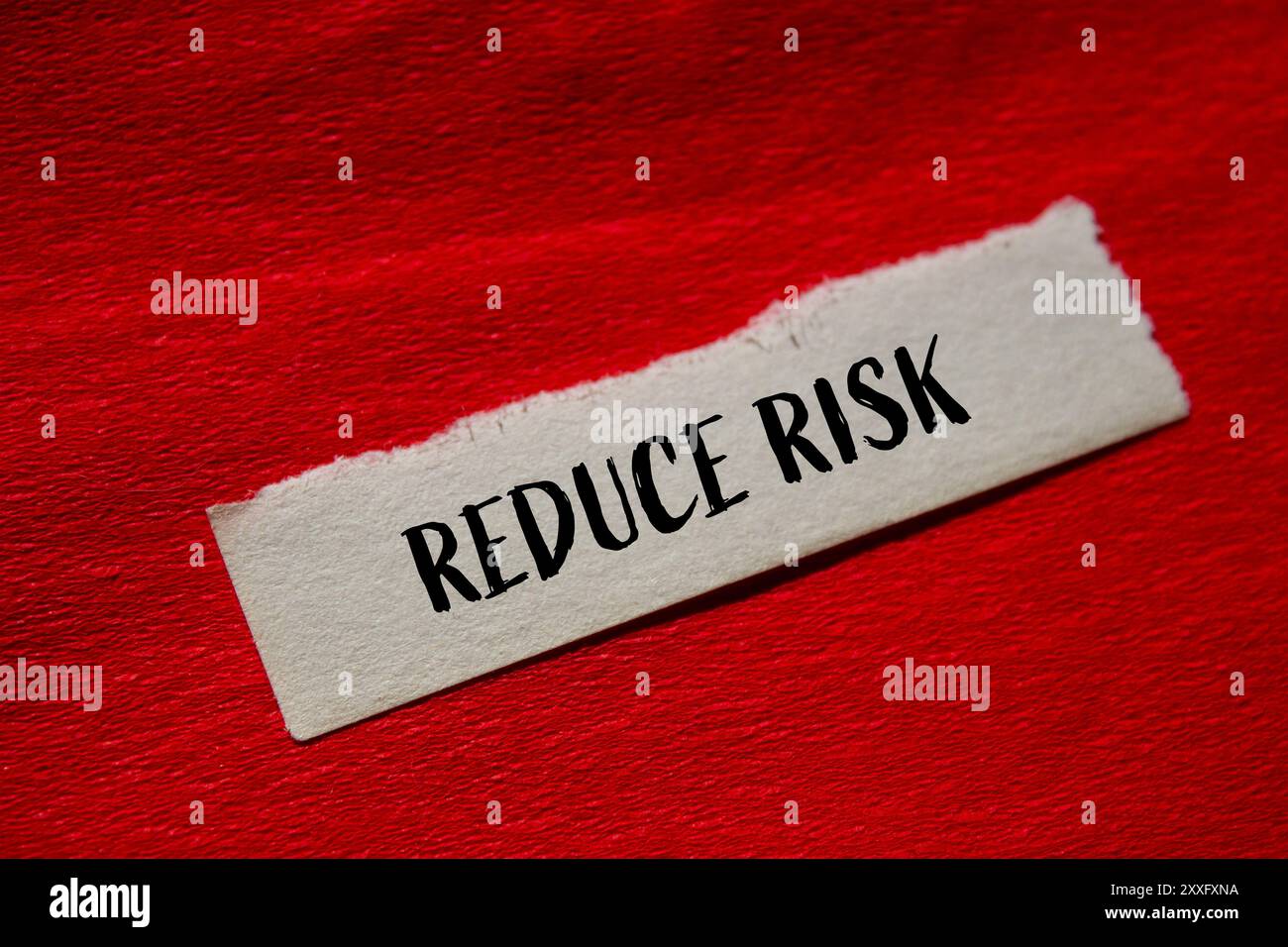 Reduce risk message written on torn paper with red background ...