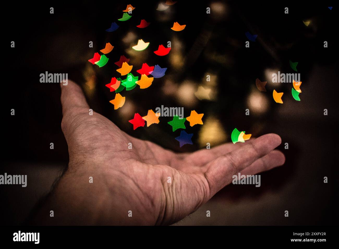 A hand throws colorful star-shaped Christmas lights - stardust Stock ...