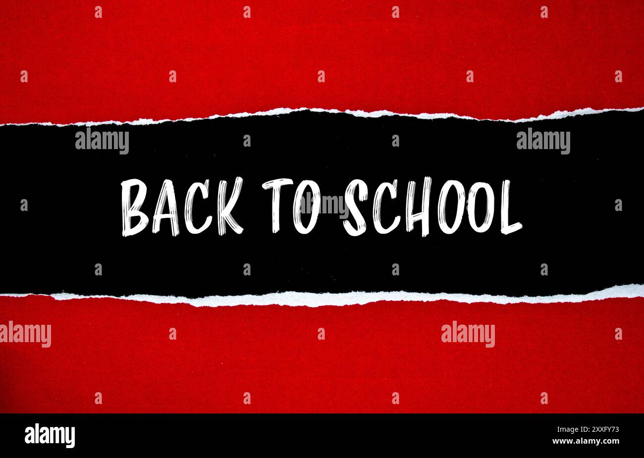Back to school message written on ripped torn red paper with black background. Conceptual back ...