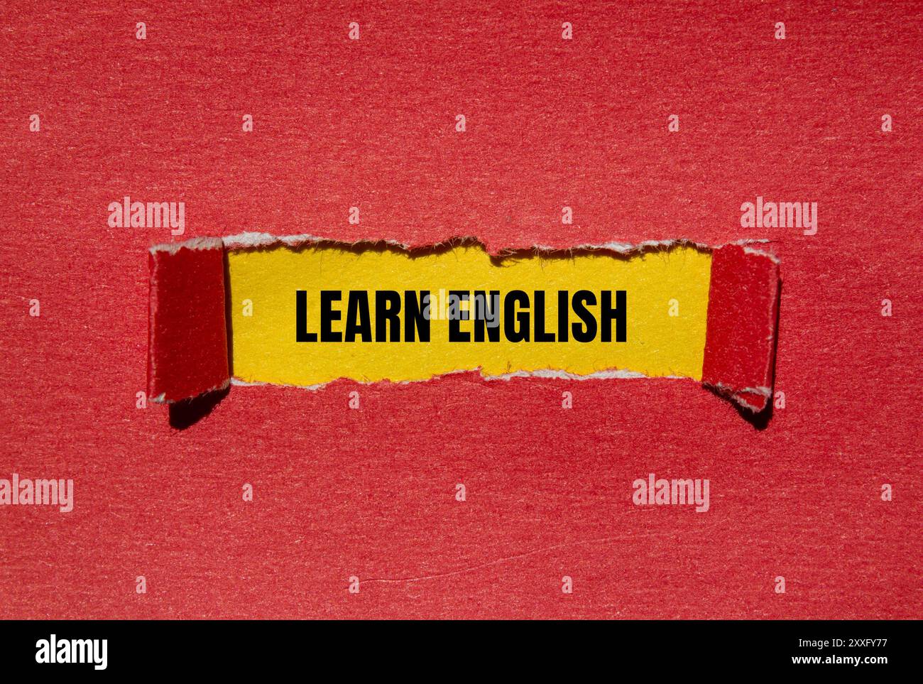Learn english message written on ripped torn red paper with yellow background. Conceptual learn ...