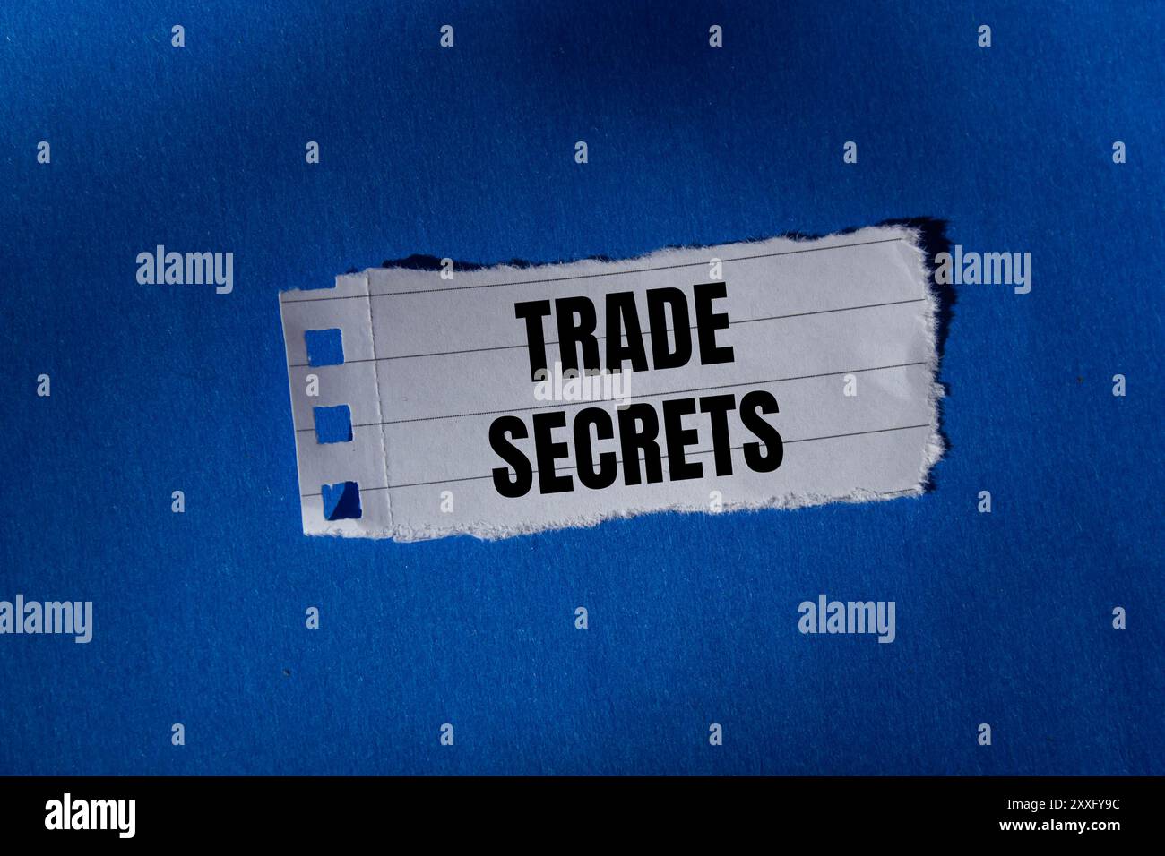 Trade secrets message written on ripped torn paper piece with blue ...