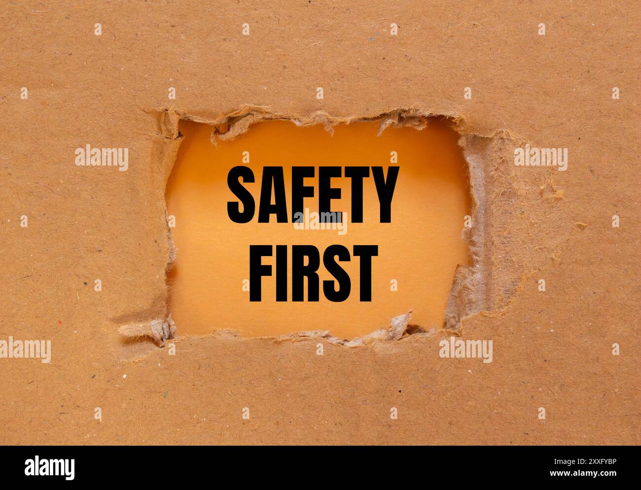 Safety first message written on ripped torn cardboard paper with orange ...