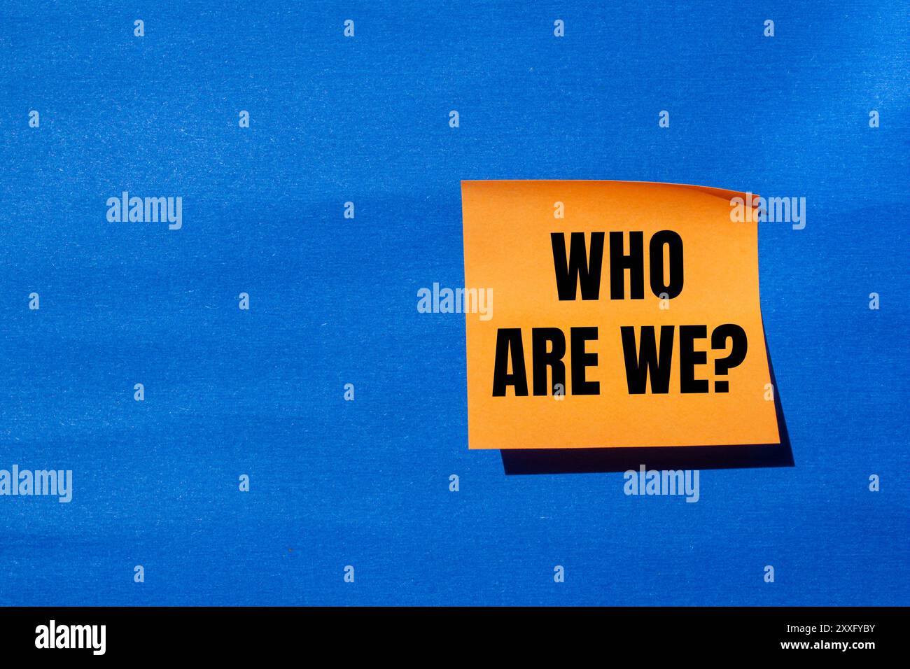 Who are we question message written on orange paper with blue ...