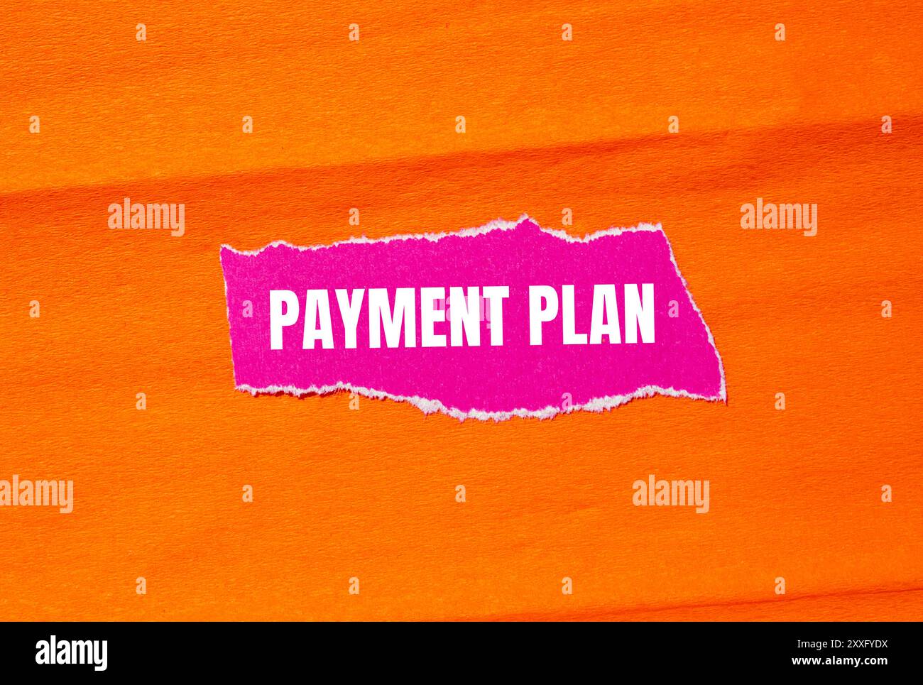 Payment plan message written on ripped torn pink paper with orange background. Conceptual ...