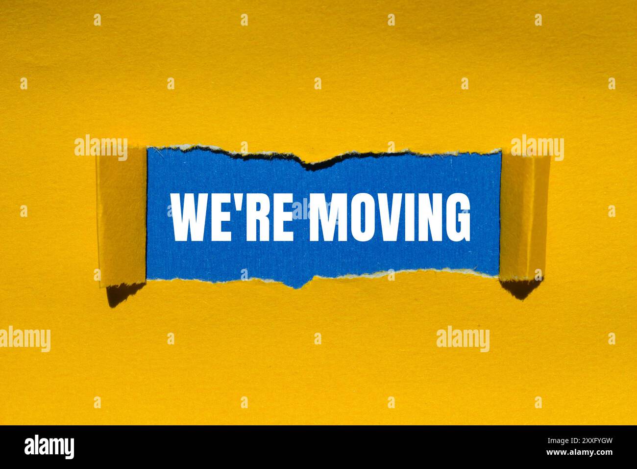 We are moving message written on ripped torn yellow paper with blue background. Conceptual we ...