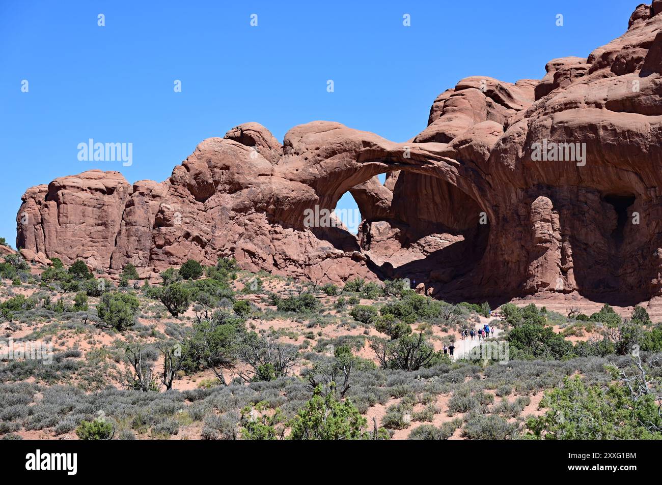 Distant tourists on Double Arch trail in Arches National Park near Moab ...