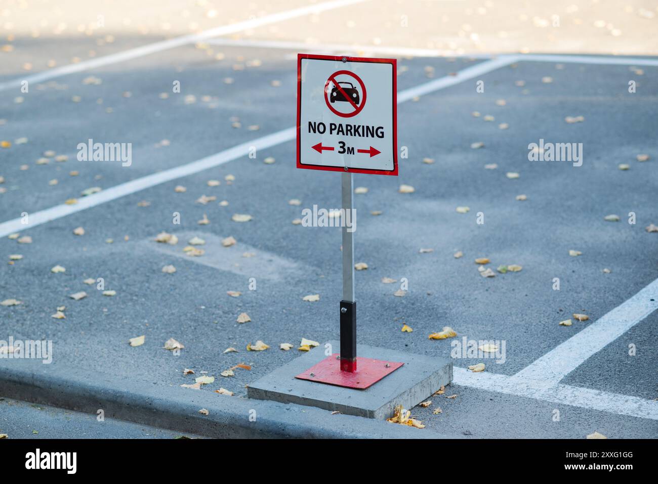 A "No Parking" sign in an empty parking lot. The pavement is partially ...