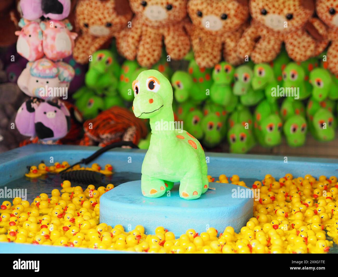 Dragon plushie toy in the amusement park with yellow ducks and lots of ...