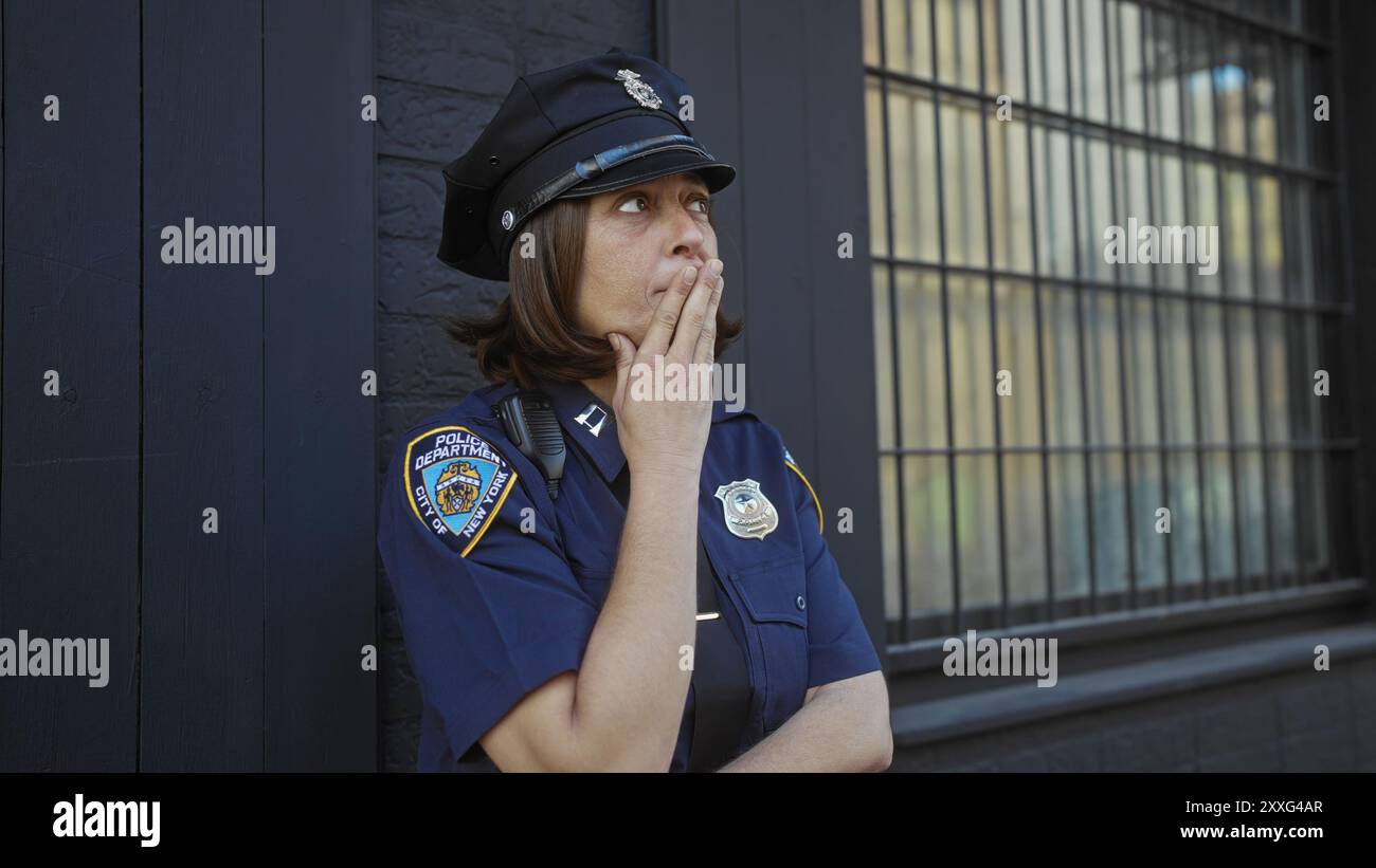 An anxious woman police officer in uniform stands worriedly outdoors ...