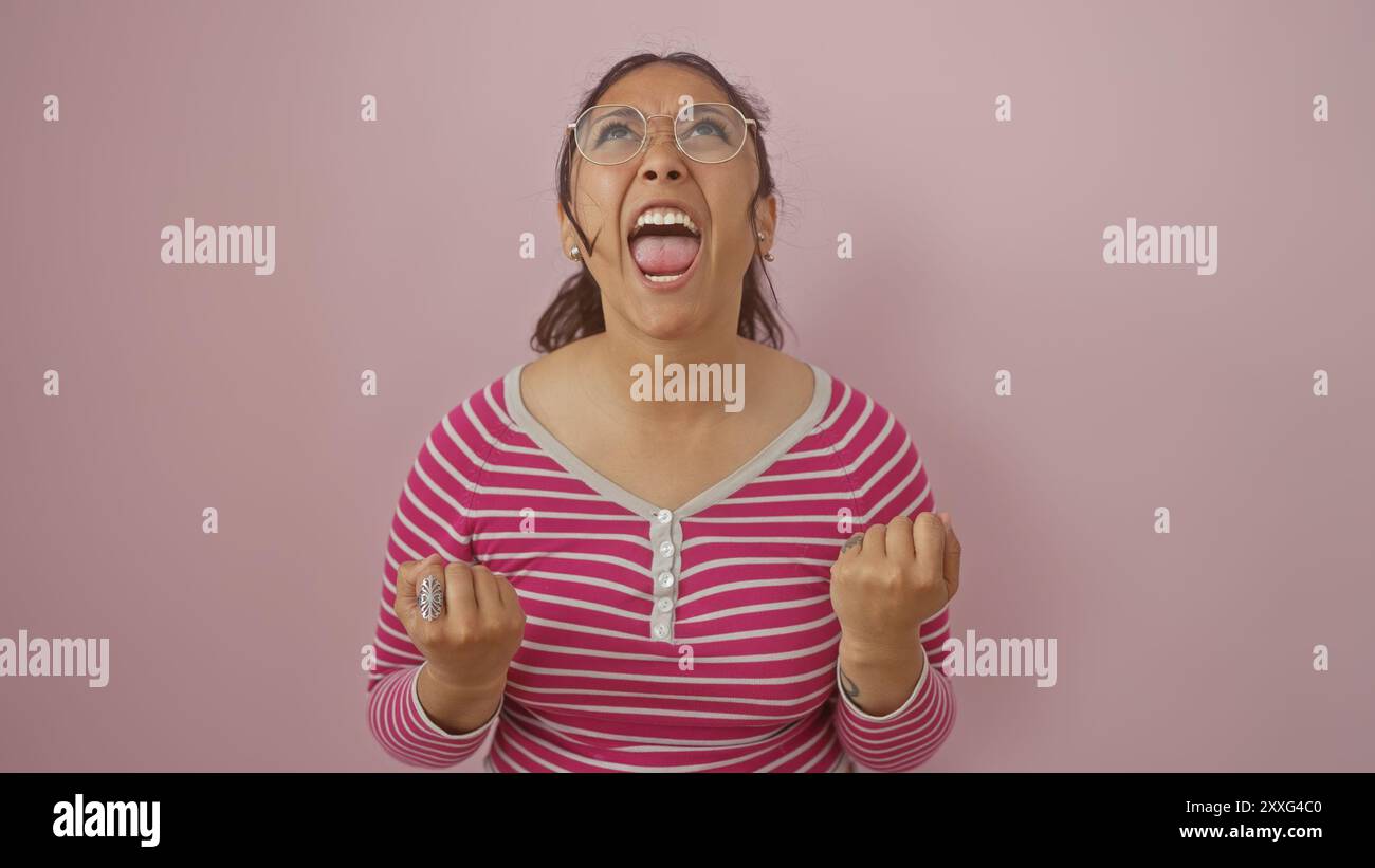 Angry young hispanic woman screaming, with a pink wall background ...