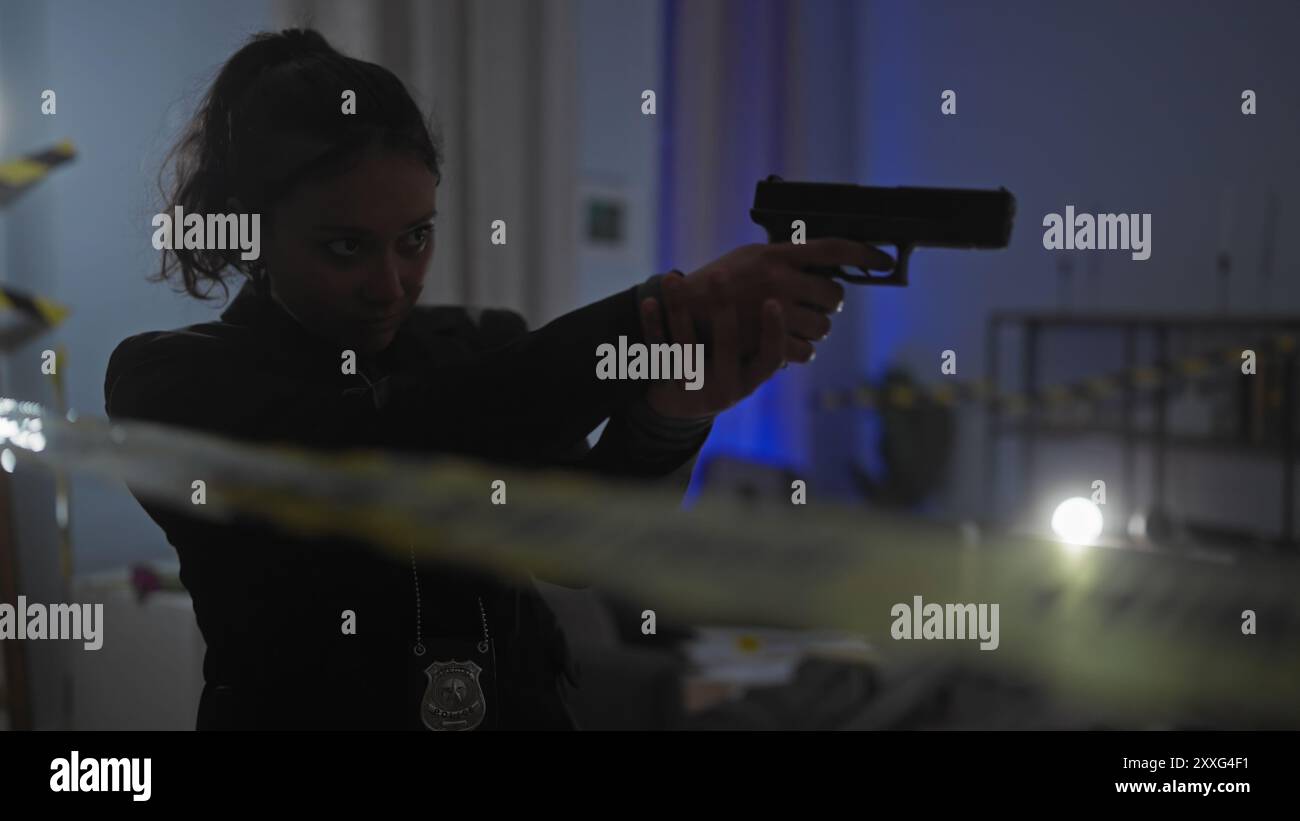 Young hispanic female detective aiming a gun at a crime scene indoors ...