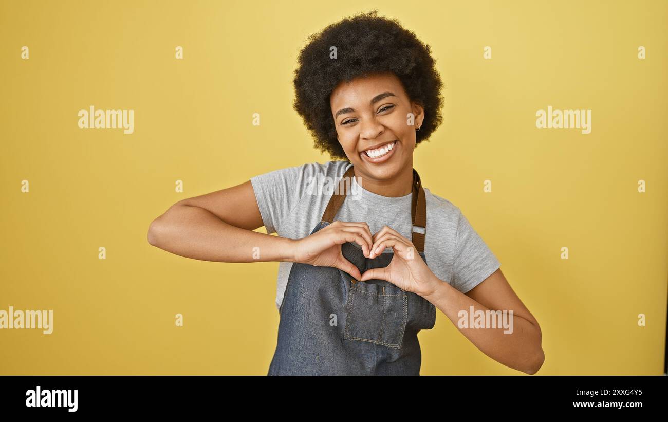 African american woman with curly hair making a heart shape with hands ...