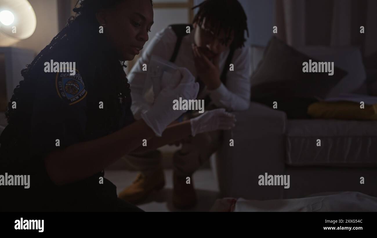 A policewoman and male investigator examine evidence indoors at a new ...