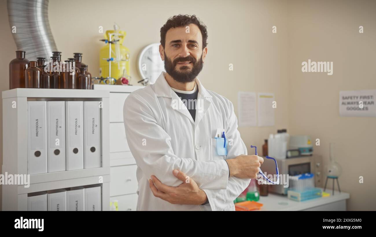 Confident bearded scientist standing in a laboratory with arms crossed ...
