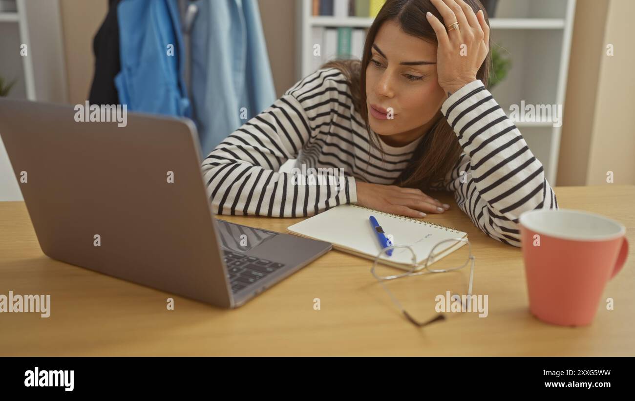 A concerned hispanic woman works at home, with a laptop, notebook ...