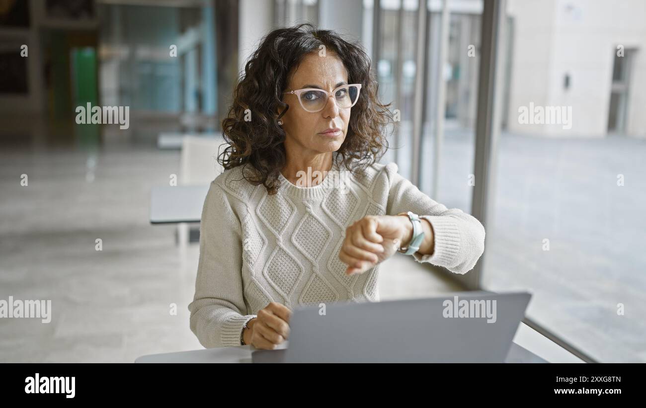 Hispanic businesswoman checks time in a modern office setting ...