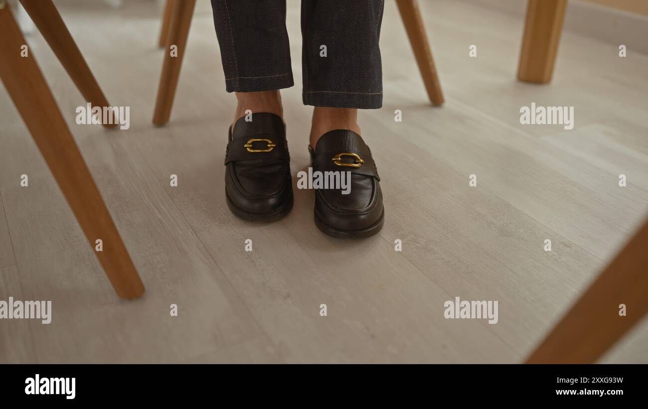 Close-up of a woman's feet wearing stylish black loafers under a wooden ...