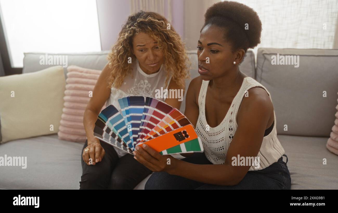Women friends choosing color swatches at home together in a living room ...