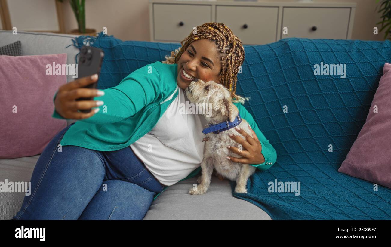 A young african american woman with braids takes a selfie with her dog ...