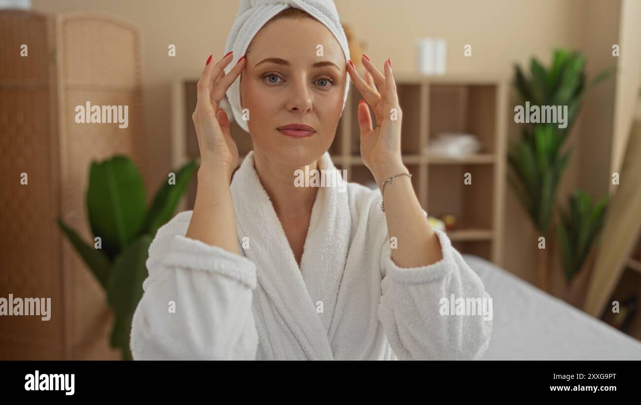 Woman relaxing in a spa room wearing a white robe with a towel wrapped around her head ...