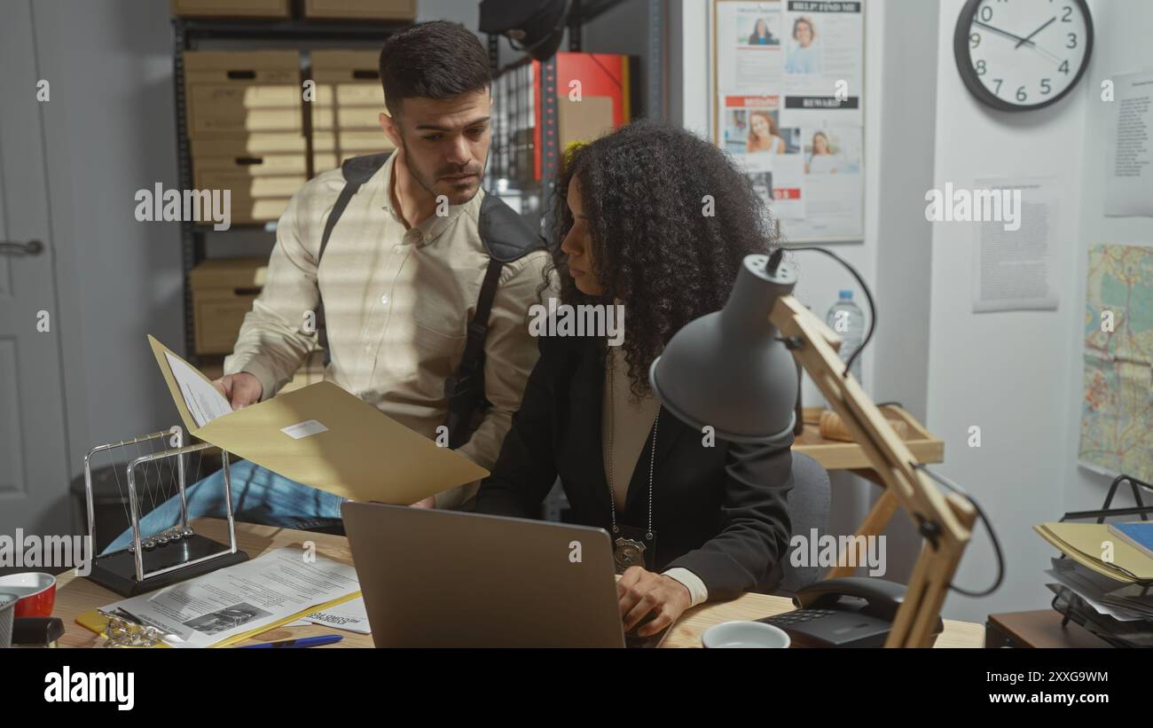 A man and woman, both detectives, inspect documents at an office ...