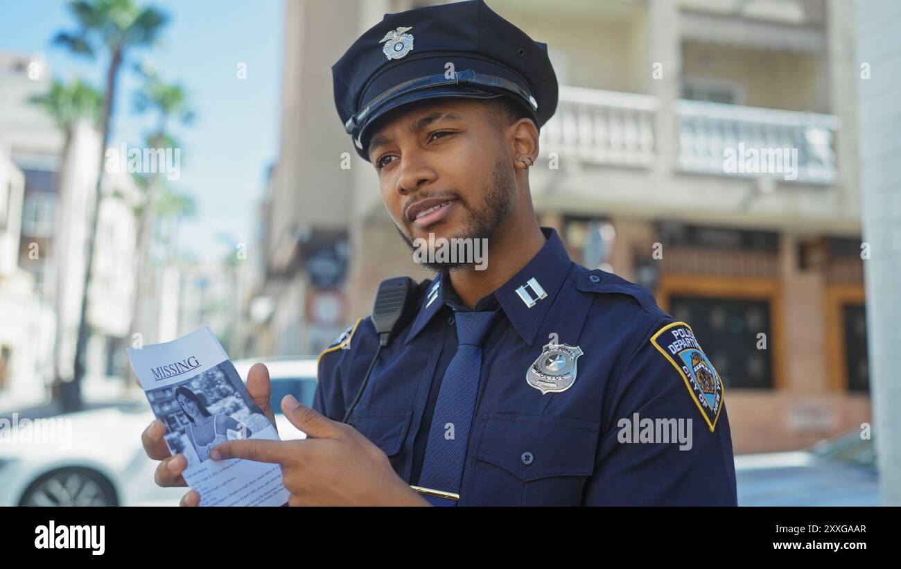 African american police officer holding a missing person flyer on a sunny city street Stock ...