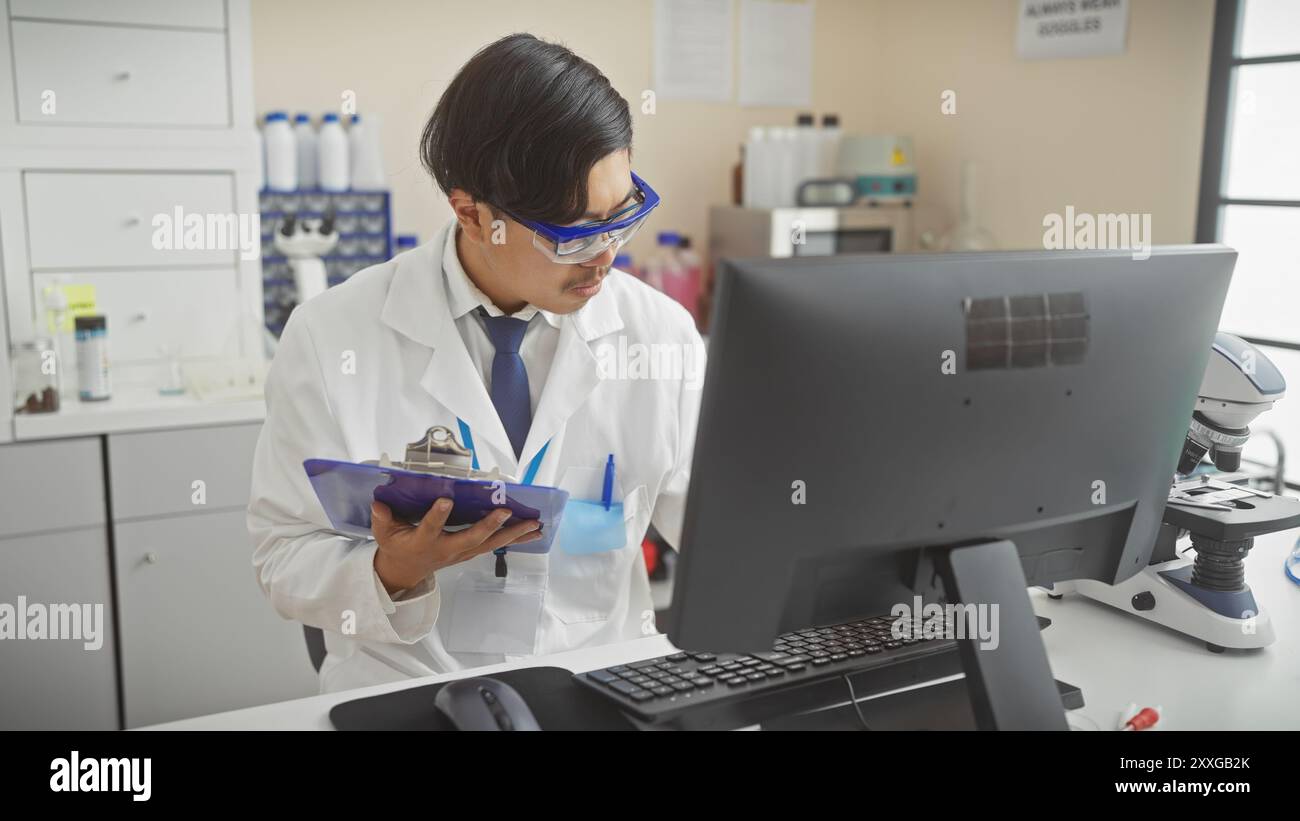 Handsome asian man in lab coat studying data on computer inside modern ...